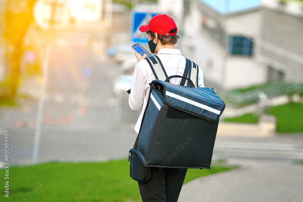 Food delivery boy with black thermal backpack using phone. Boy ...