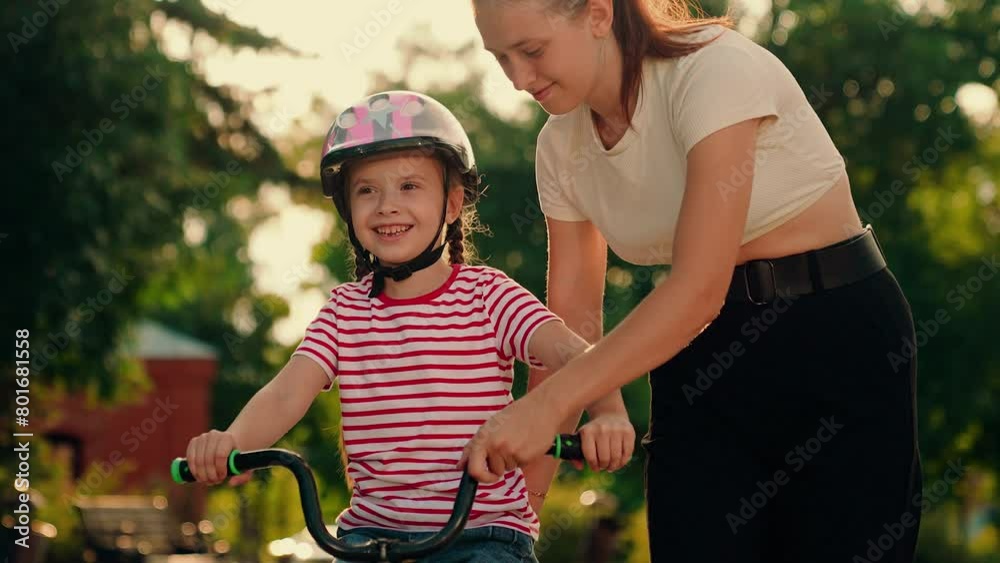 Sister teaches kid girl to ride bike in park. Child cyclist with mom ...