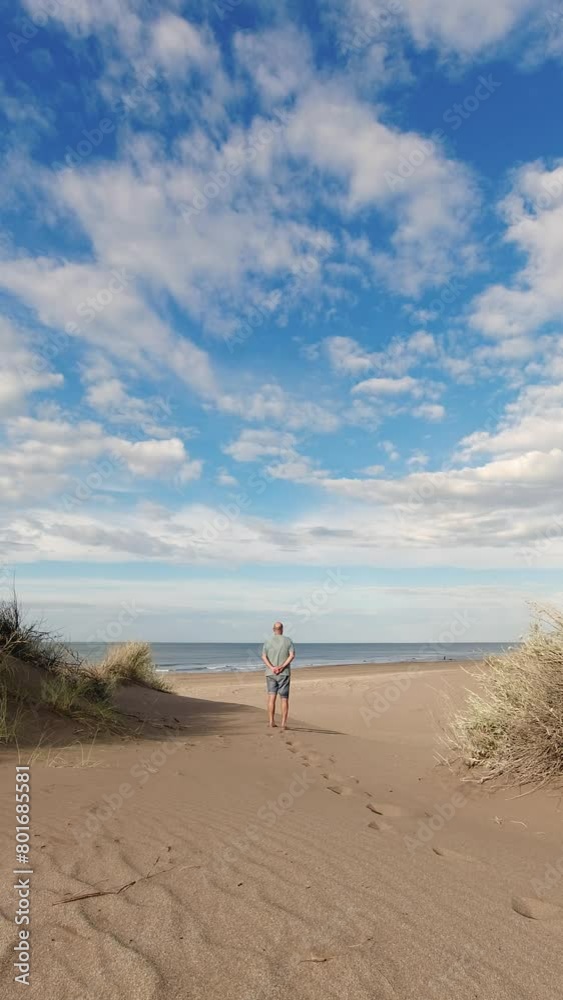 Senior man, hands crossed behind his back, seen from behind standing on ...