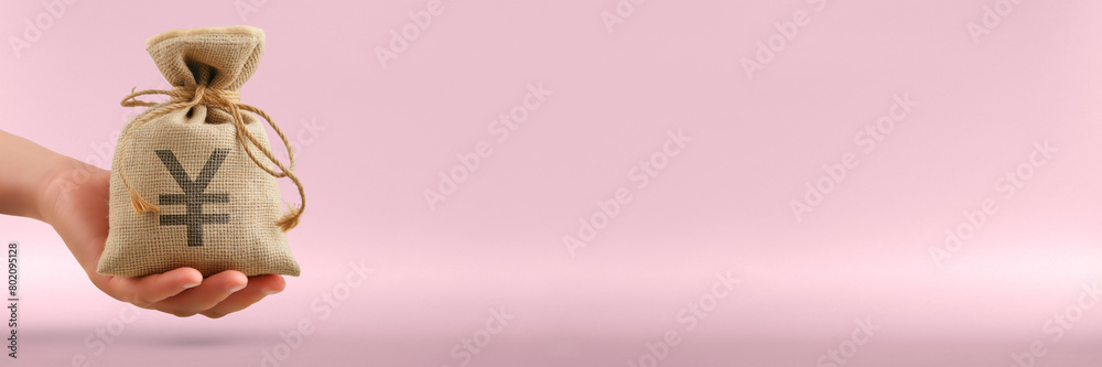 Hand holding a money bag with the Chinese yuan symbol on a pink ...