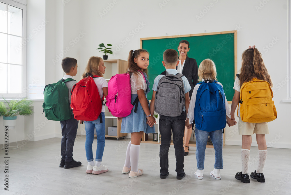 Schoolchildren with colorful backpacks on their shoulders are holding ...