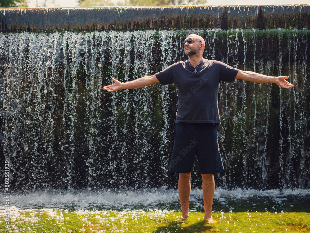 Bald man doing workout with his own body weight in a stream by a ...