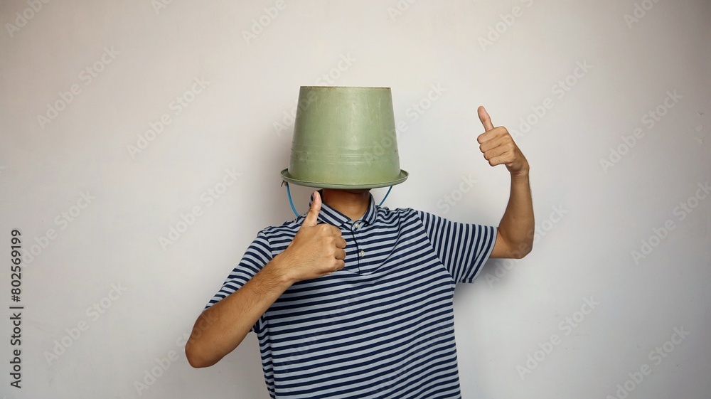 young man using a bucket on his head on a white background. showing ...
