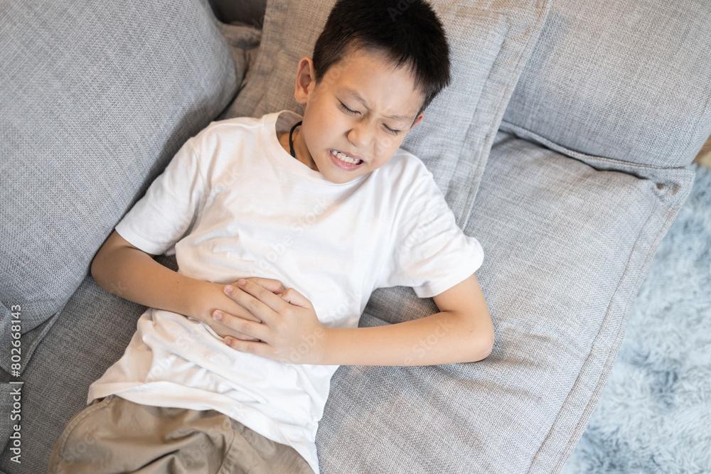 Sick asian child boy suffering from stomachache,holding his belly ...