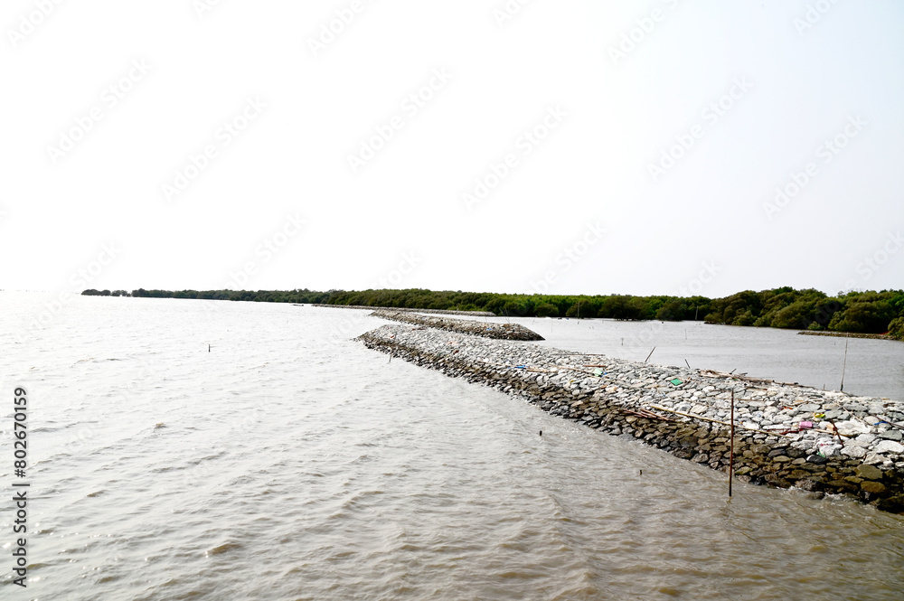 Walls of large and small rocks line the beach to protect the beach and ...