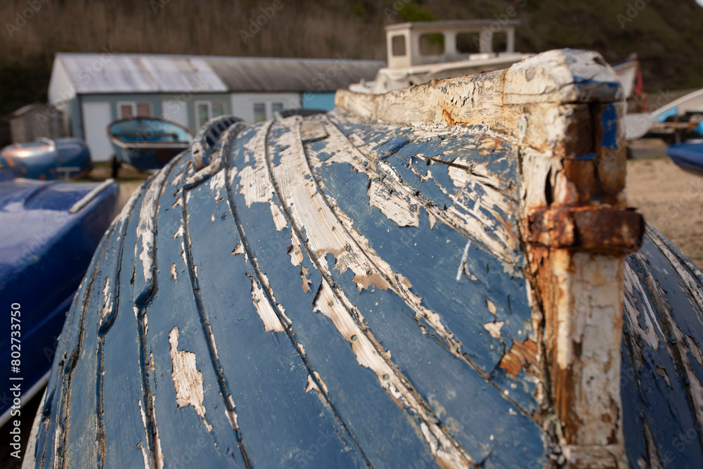 Old damaged wooden rowing boat with flaking paint left abandoned on the ...