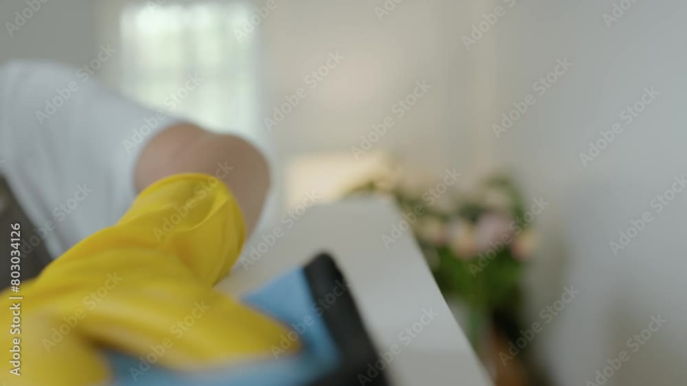 she is doing housework to keep the house clean, wearing glove to ...