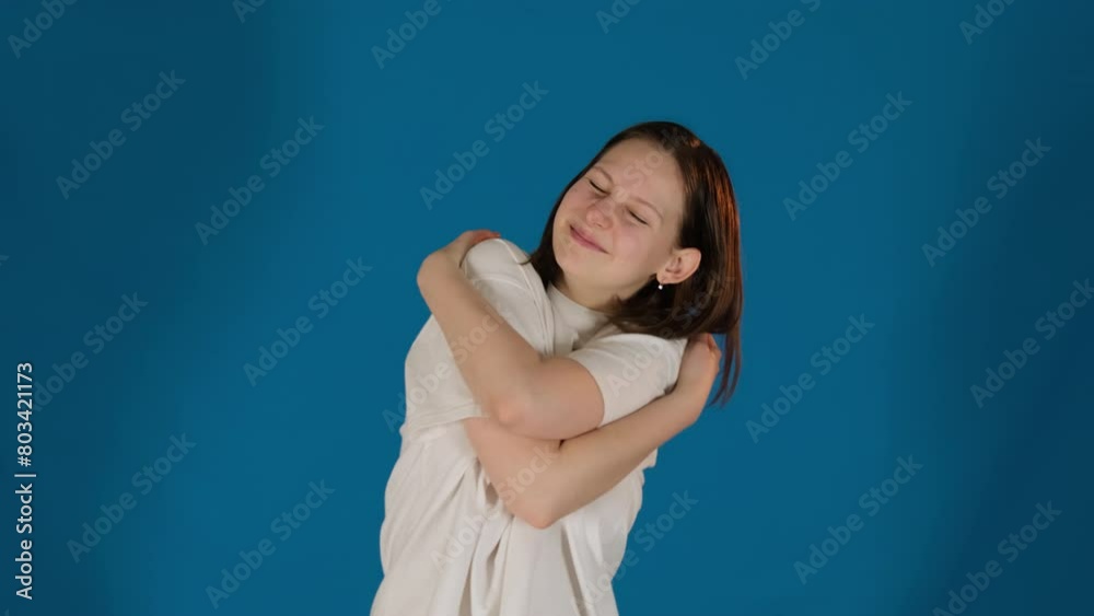 Lady embraces body with arms feeling happiness on blue background ...