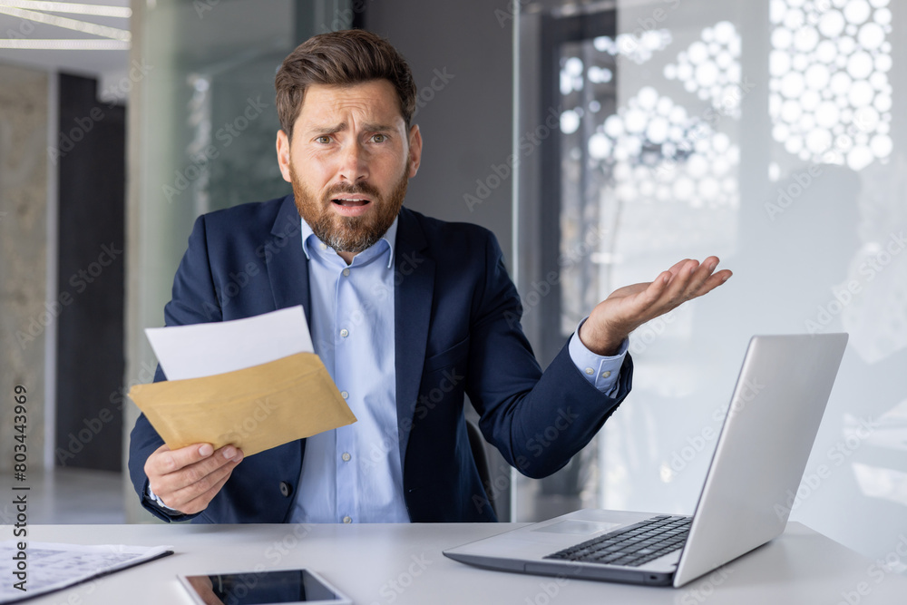Frustrated businessman looking confused at document in office Stock ...