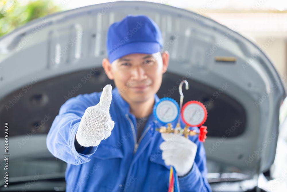Repairman showing thumbs up and holding monitor tool to check and fixed car air conditioner ...