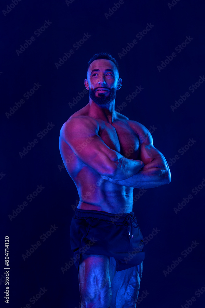 Bodybuilder in neon colors. Athlete man posing on black background ...