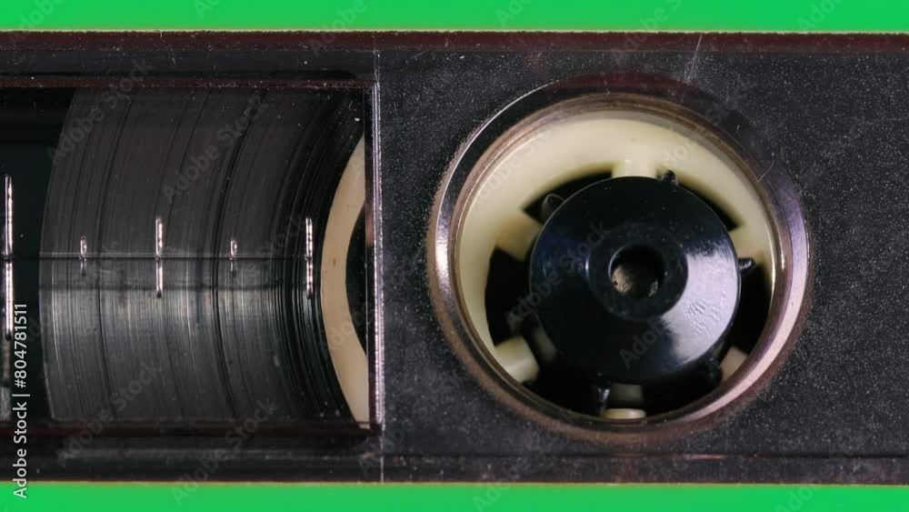 Nostalgic audio cassette tape unwinds behind a transparent window in an ...