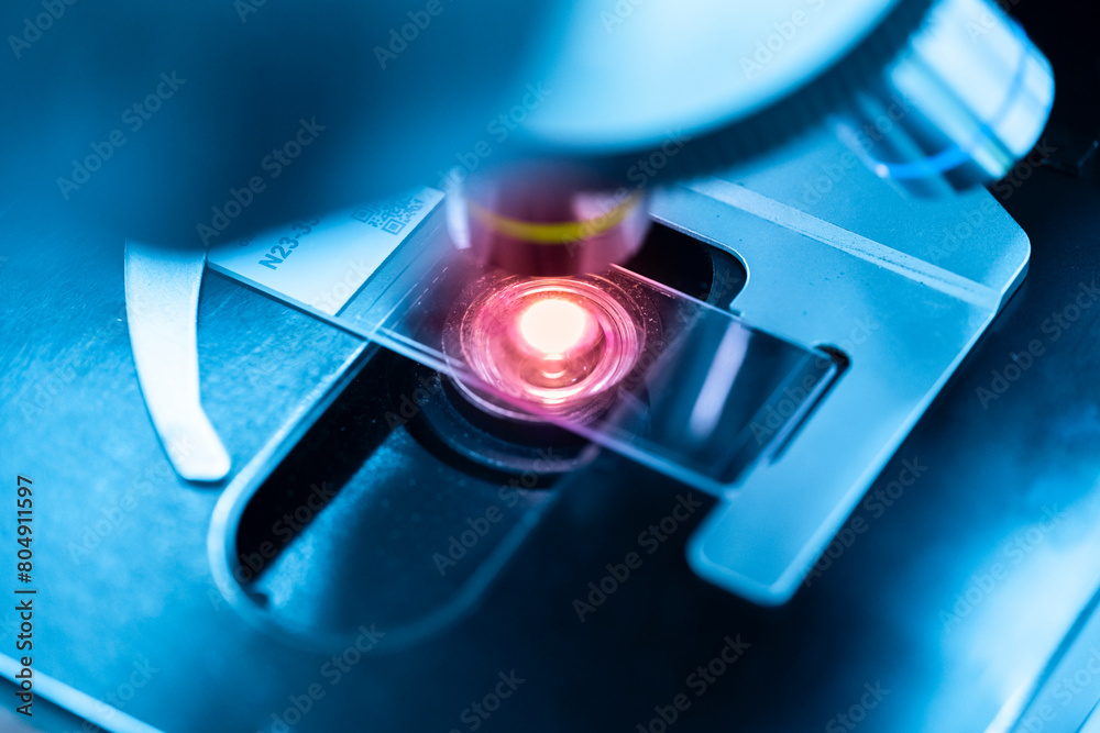 Close up and soft focus glass slide and out of focus objective lens ...