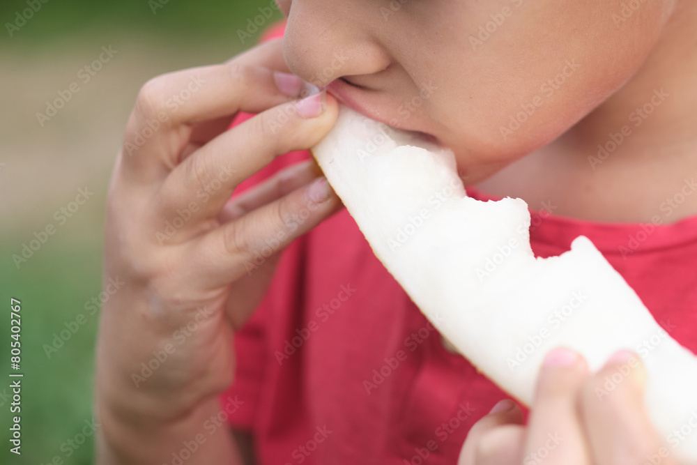 Detailed shot capturing a child's delight in biting into a juicy melon ...