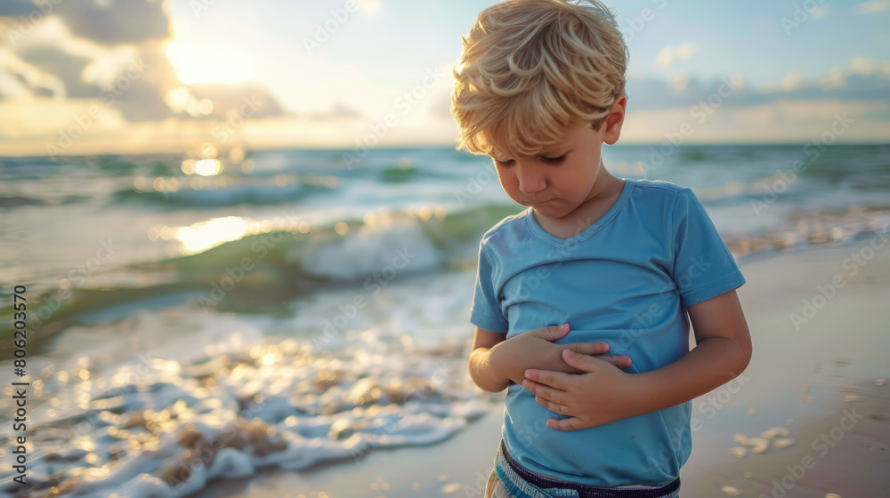 upset boy holding his sore stomach on the beach, diarrhea, poisoning ...
