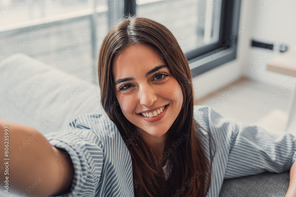 Happy attractive young adult woman housewife sitting on sofa looking at ...