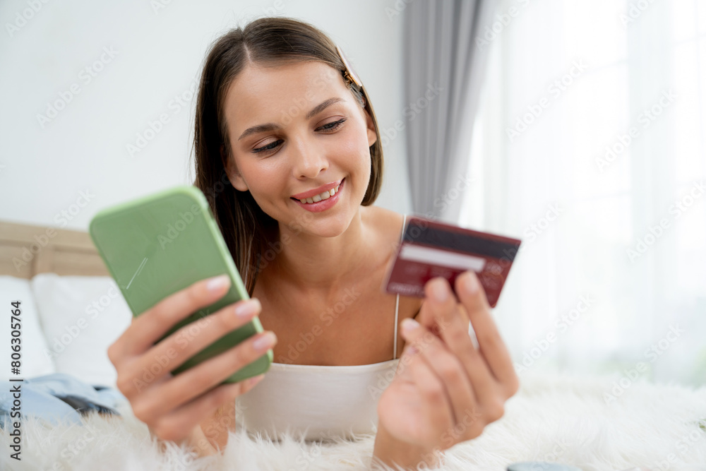 Young woman lying on the bed using online payment app and digital ...