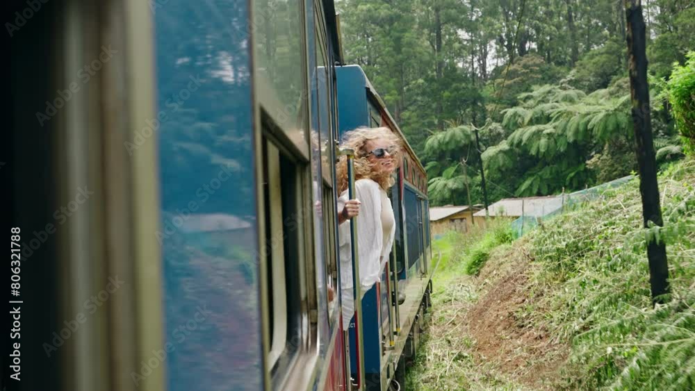 Solo female traveler leans out train door, feels wind, hair blows in breeze. Adventure in ...