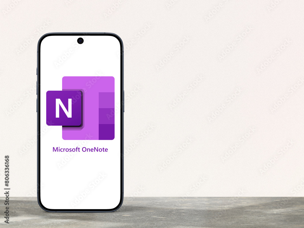 OneNote logo displayed on a modern smartphone standing on a desk, note ...