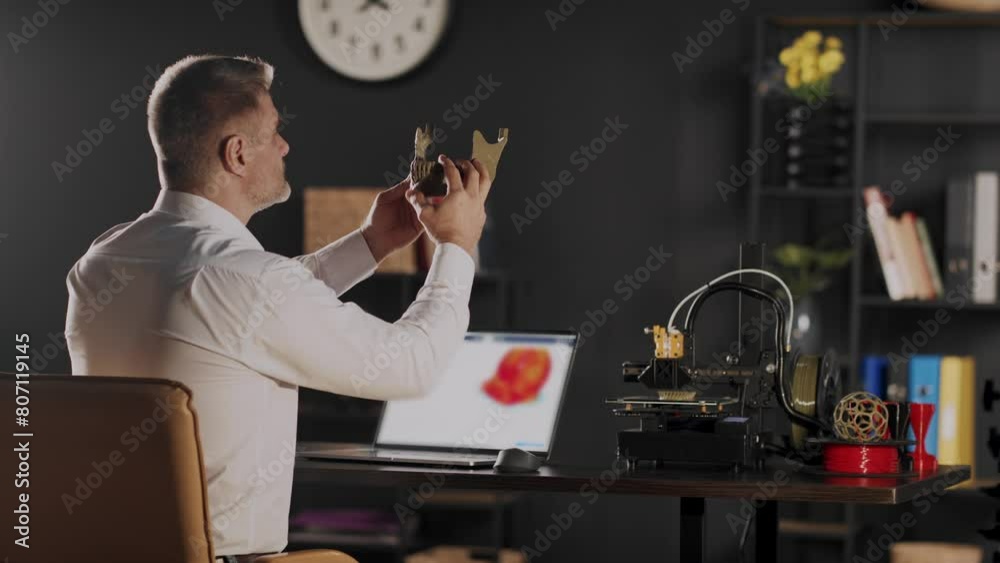 A man graphic designer sideways holds and views plastic 3d printed ...