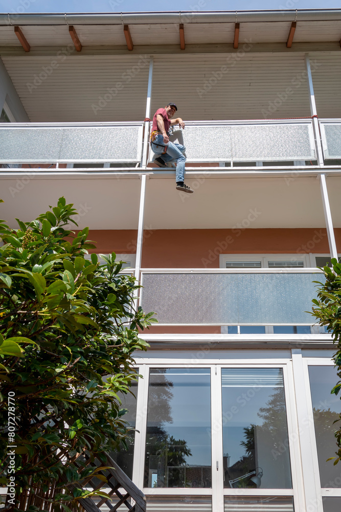 Working high-rise worker on the balcony in the house at height ...