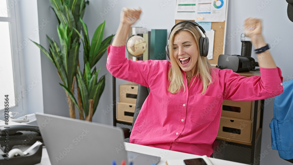 Excited woman celebrating with raised arms in a modern office setting ...