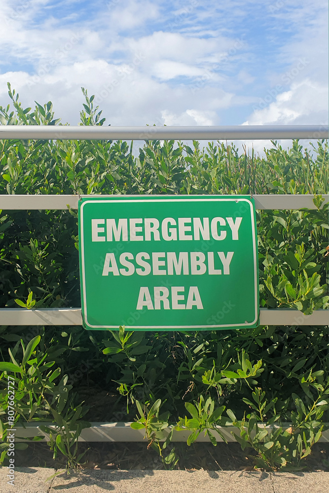 emergency assembly area, green sign tied to metal railing hanging ...