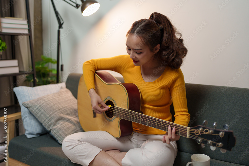 Smiling, happy young woman playing a musical instrument while ...