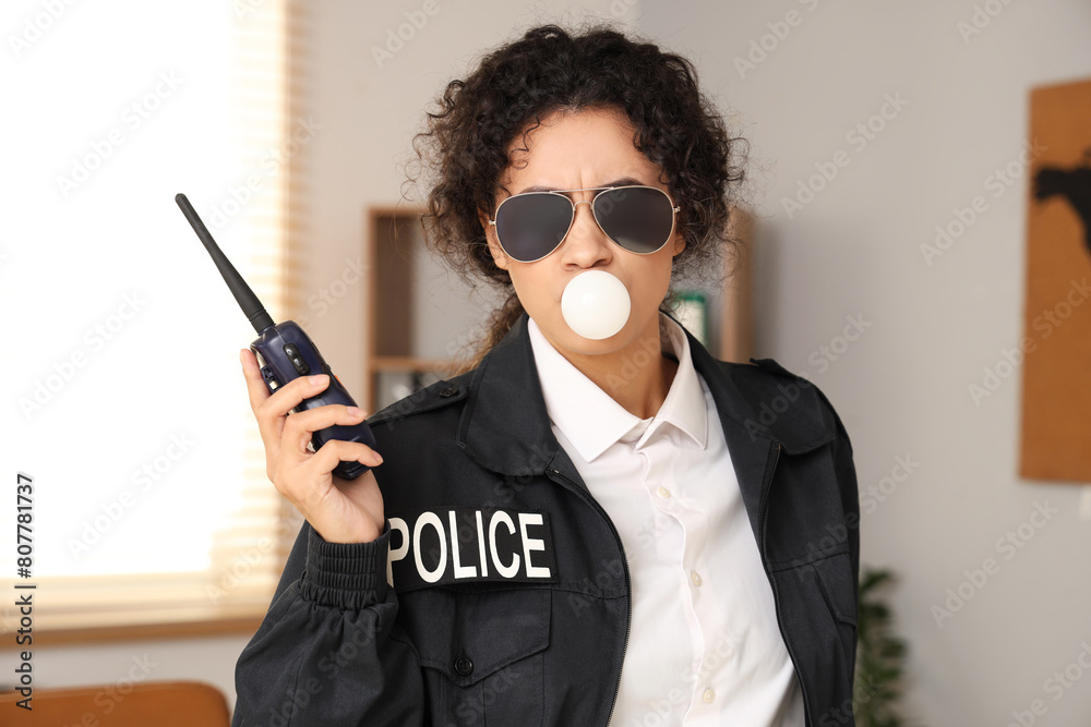 African-American police officer with radio transmitter blowing bubble ...