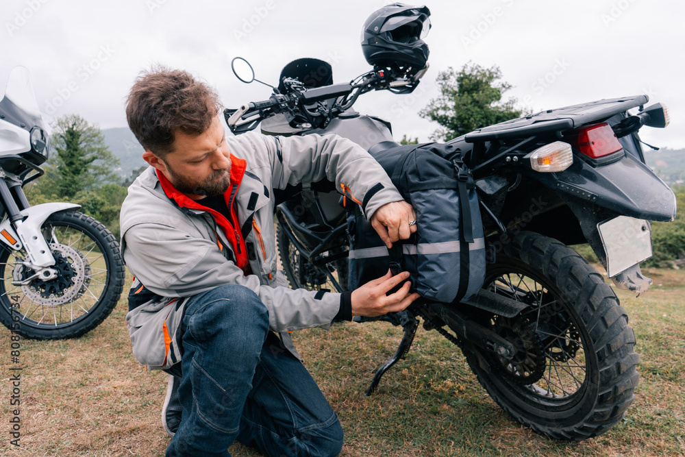 Motorcyclist packing bags on Adventure motorcycle in moto tour in ...