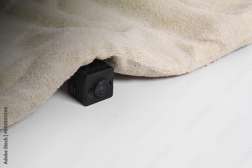 Closeup spy camera under cloth on white background. Black security ...