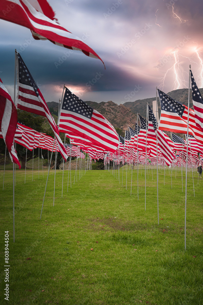 Dramatic American flag display in grassy field under stormy sky ...