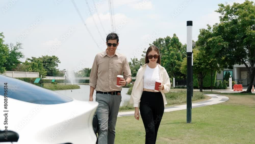 Slow motion couple recharge EV car battery at charging station ...