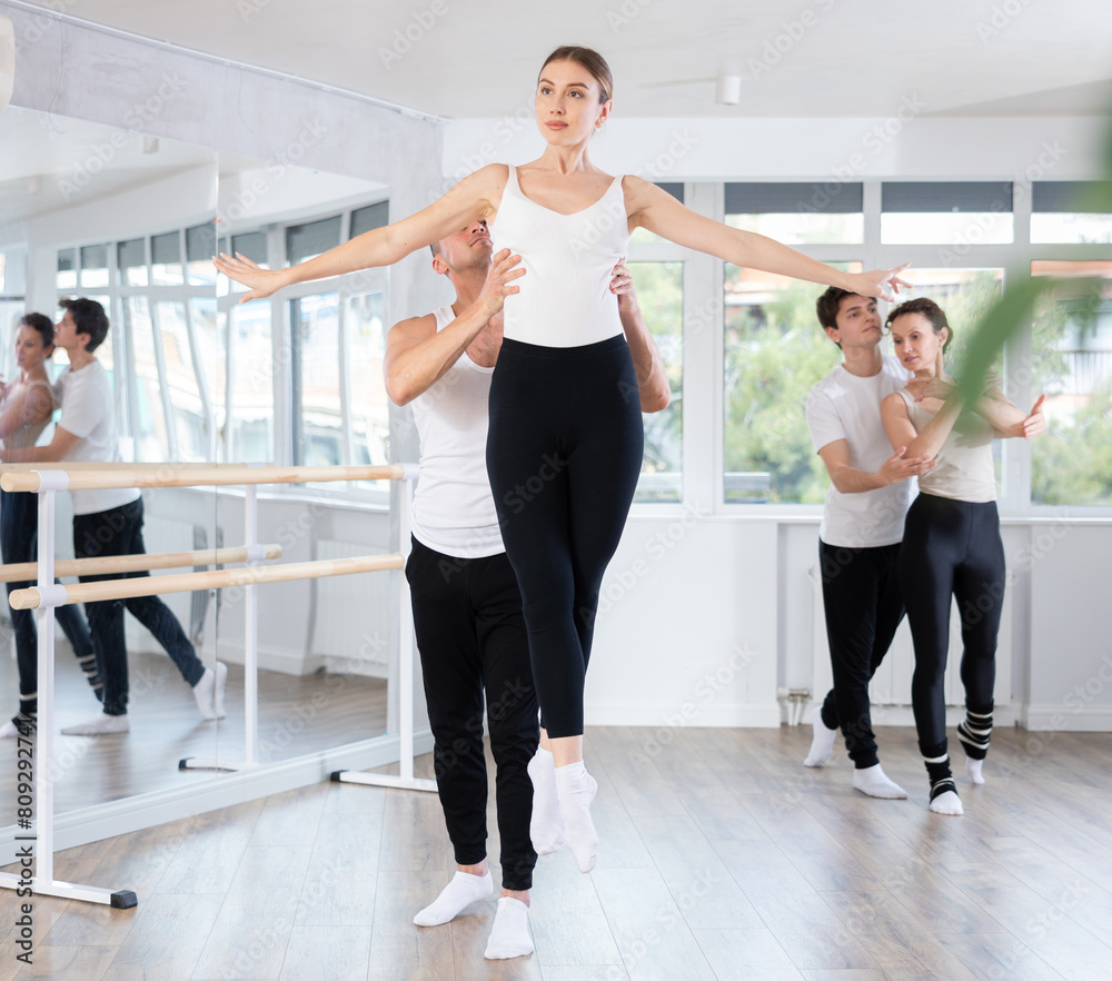 Confident leading pair demonstrating releve with assistance during ...