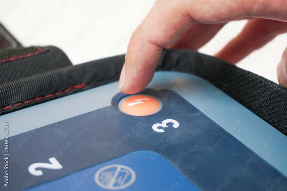pressing the AED's shock button to deliver an electric shock to a heart ...