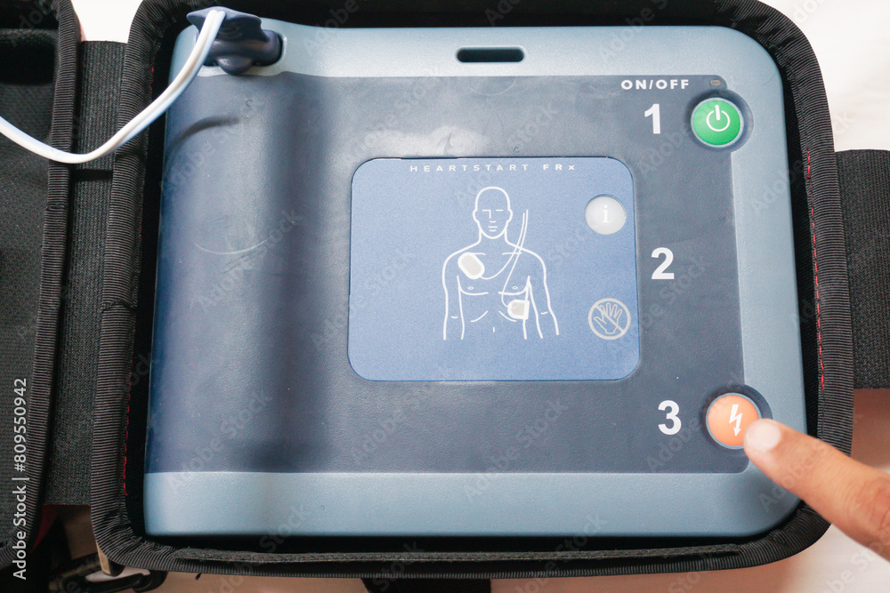pressing the AED's shock button to deliver an electric shock to a heart attack patient Stock ...