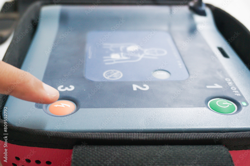 pressing the AED's shock button to deliver an electric shock to a heart ...