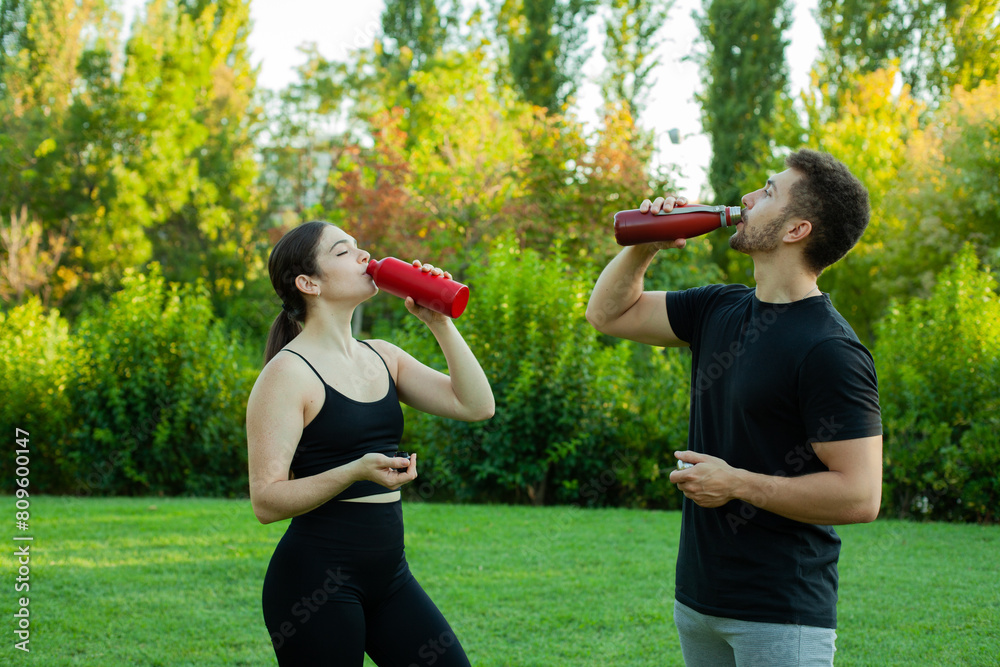Pareja bebiendo agua en un parque. Mujer y hombre deportistas. Deporte ...