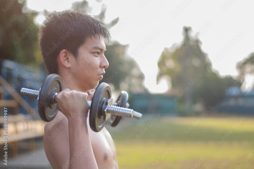 Asian preteen boy lifting dumbbells to loose weight and to do the ...