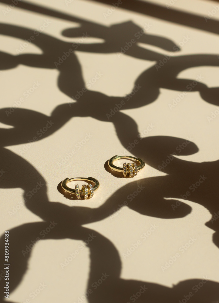 Gold earrings with crosses on beige background. Still life and creative ...