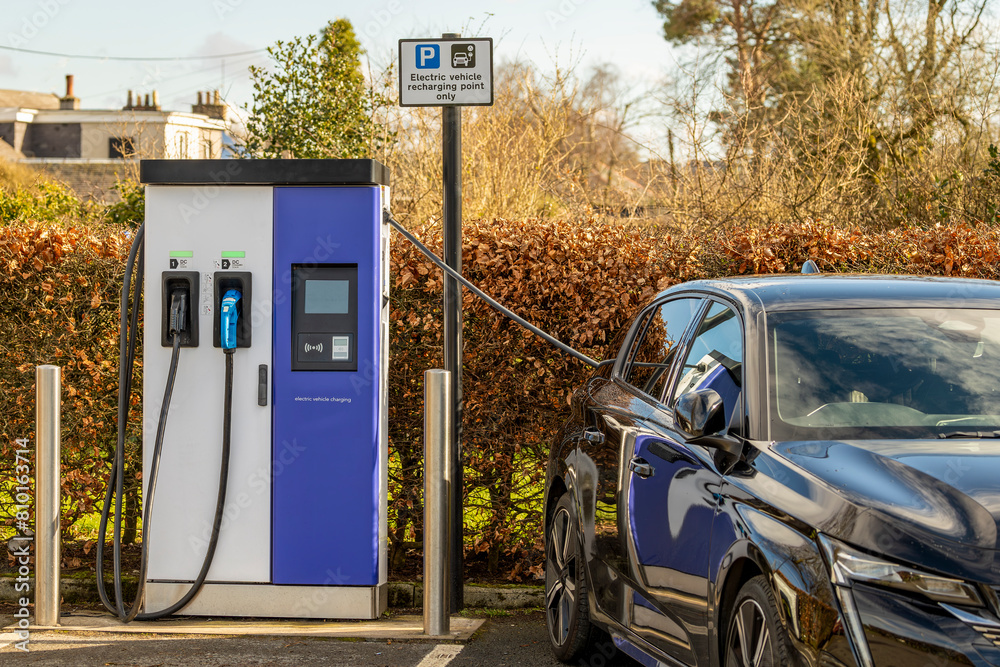 Public electric vehicle (EV) car charging station in local car parking ...