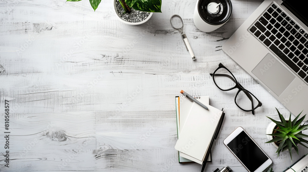 Top-down view of a white desk featuring a laptop, smartphone, glasses ...