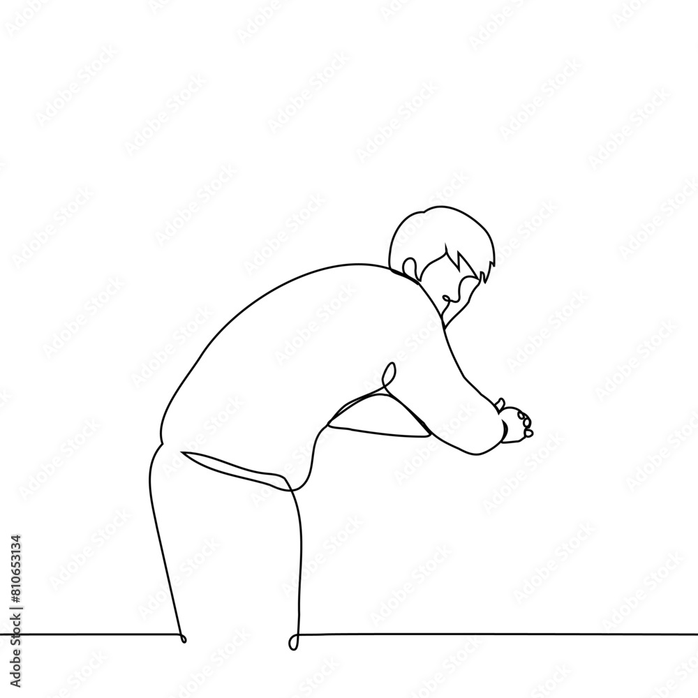 man stands leaning forward leaning on crossed elbows and turned around ...