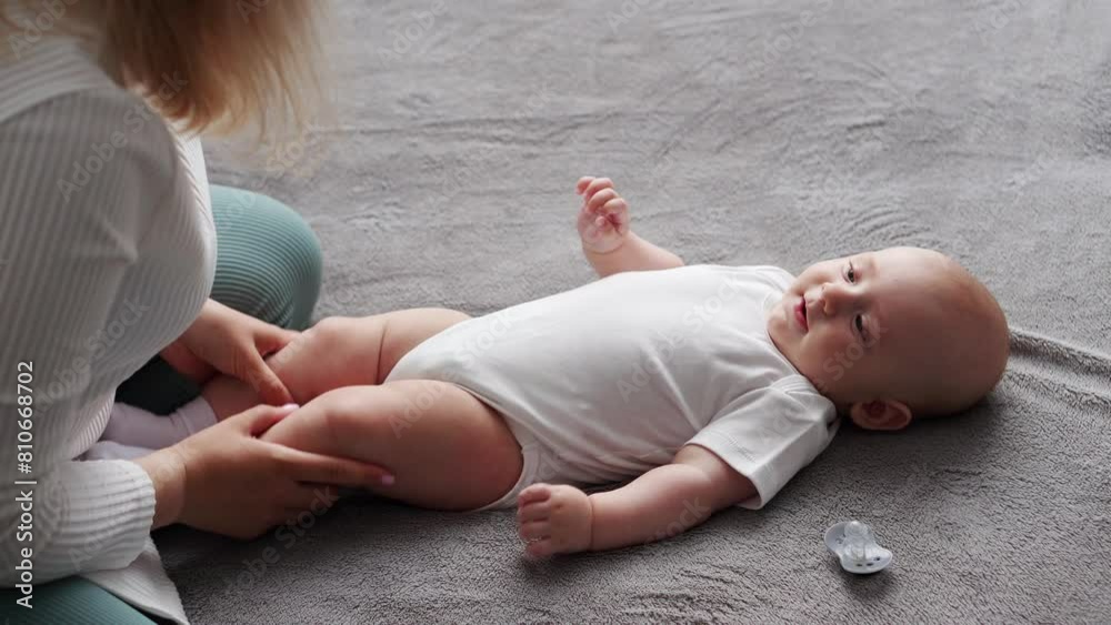 Baby lies on bed at home, mom does morning exercises for infant ...