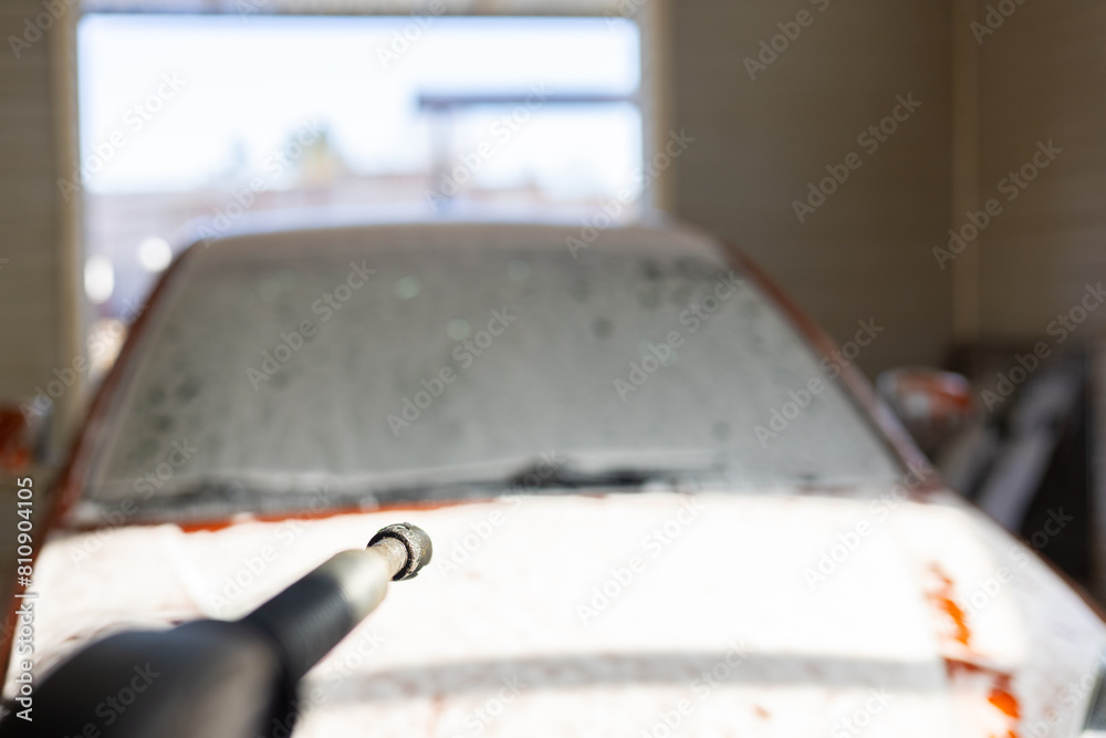 Zdjęcie Stock: A man holds a gun in his hand at a car wash and covers ...