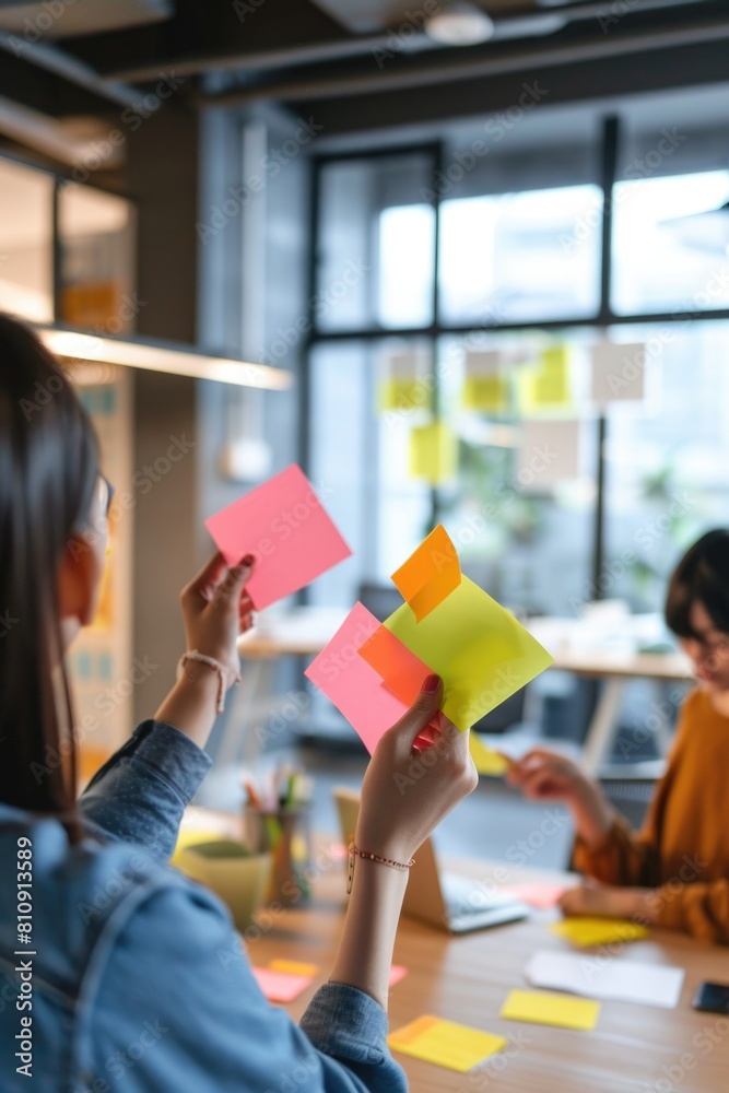 In the office, two women are discussing ideas and sorting through ...