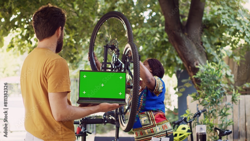 Young man with laptop displaying greenscreen as african american lady ...