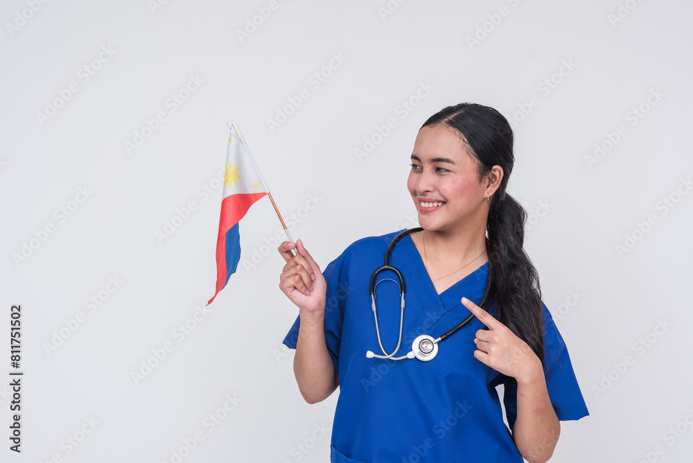 A young Filipino female nurse wearing blue scrubs, pointing to a ...