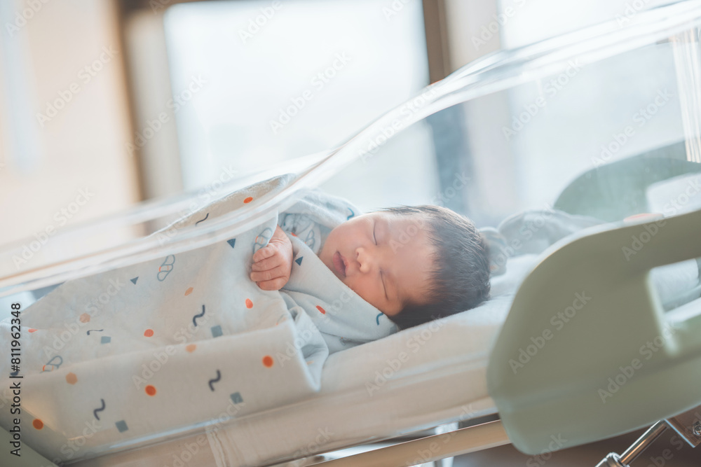 Cute little Asian newborn baby lying in crib in a maternity hospital ...