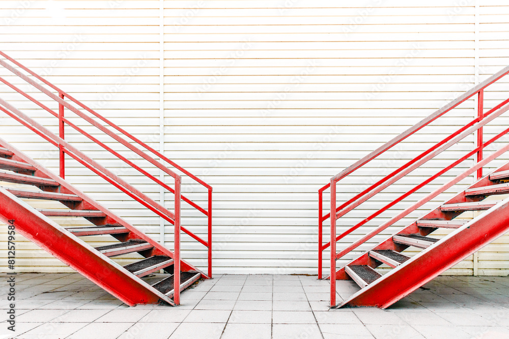 two red metal stairs on the background of a wall finished with siding ...